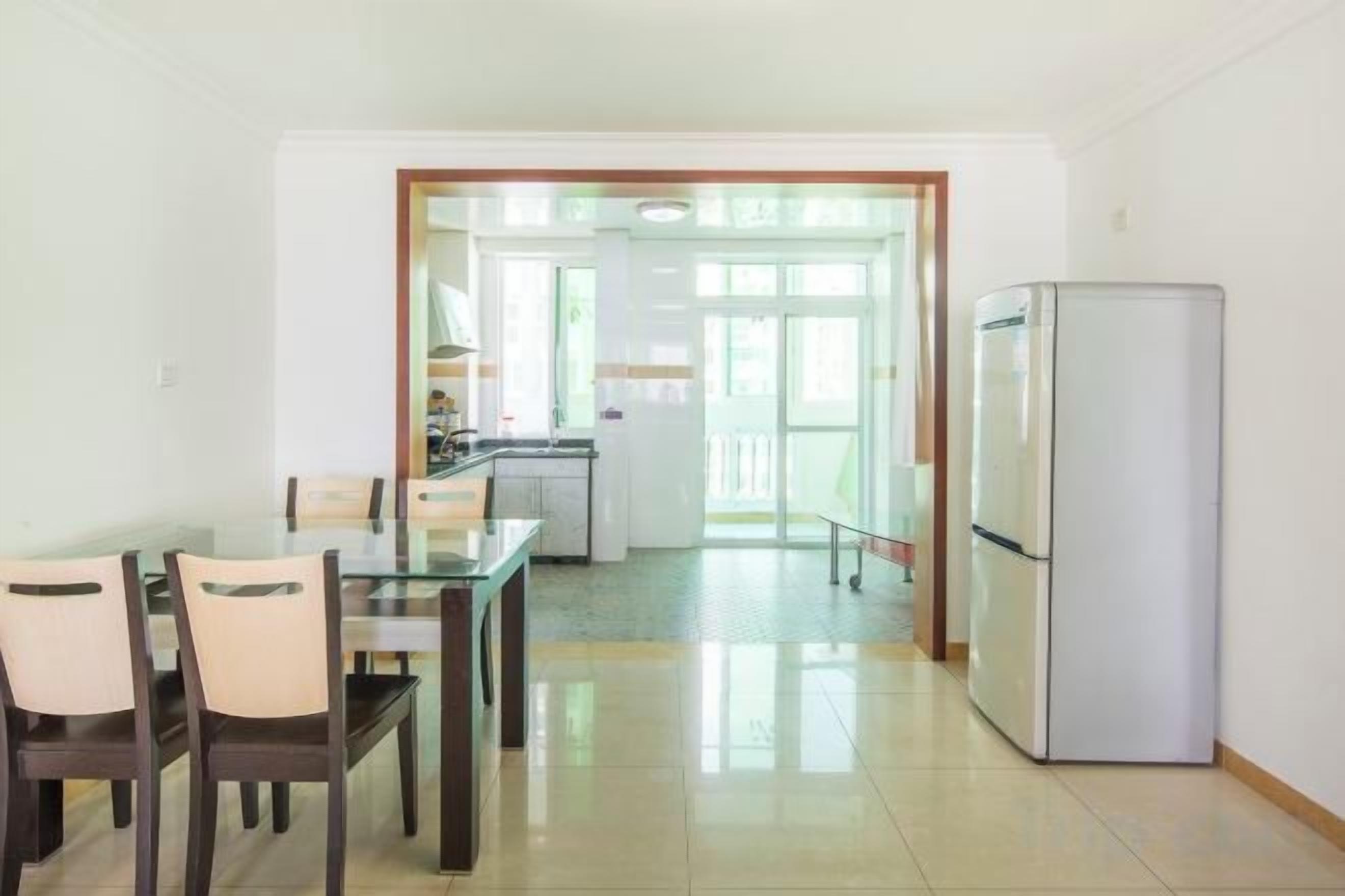 Cozinha moderna com geladeira, mesa de jantar com cadeiras e vista para a sala de estar.
