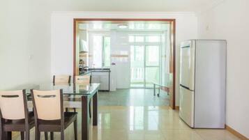 Cozinha moderna com geladeira, mesa de jantar com cadeiras e vista para a sala de estar.