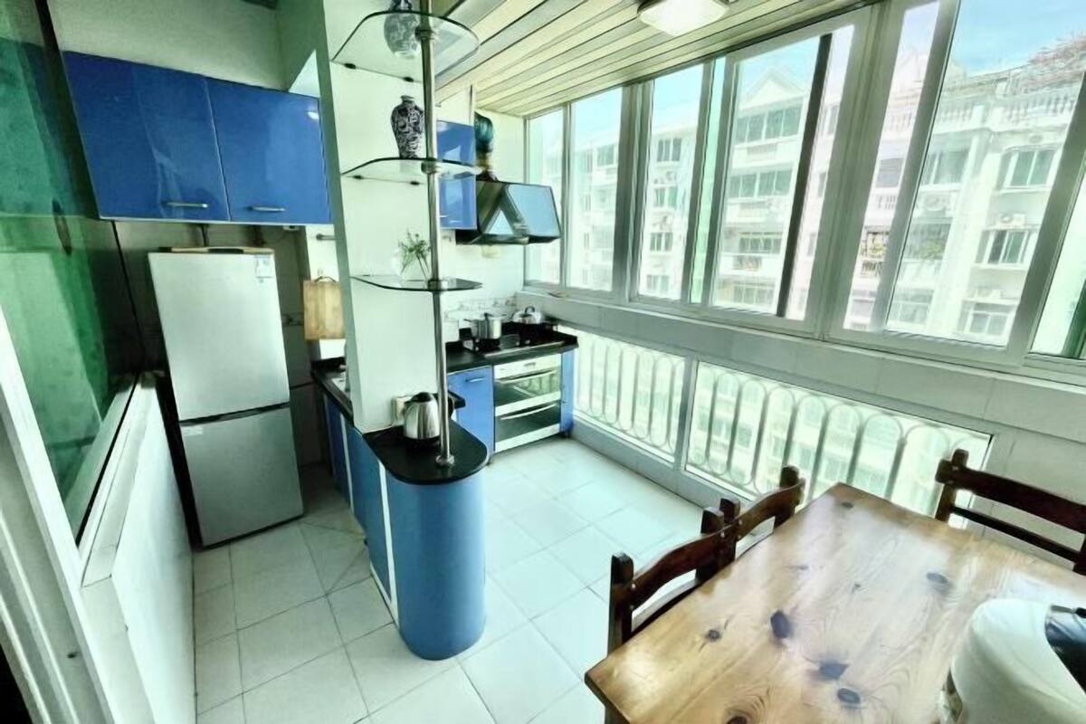 Cozinha compacta com área de refeições, janelas amplas e vista para edifícios.