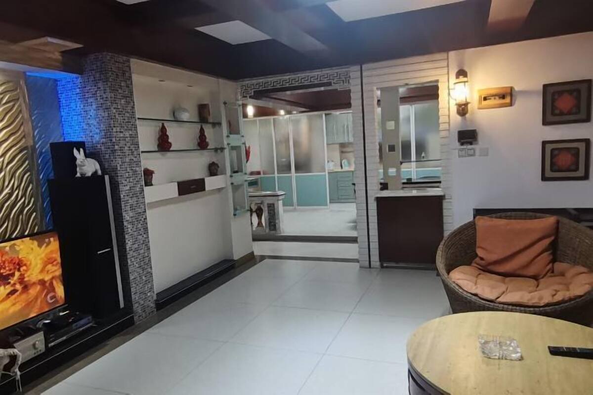 Uma sala de estar moderna com uma televisão de tela plana, uma poltrona de vime e uma mesa de jantar.