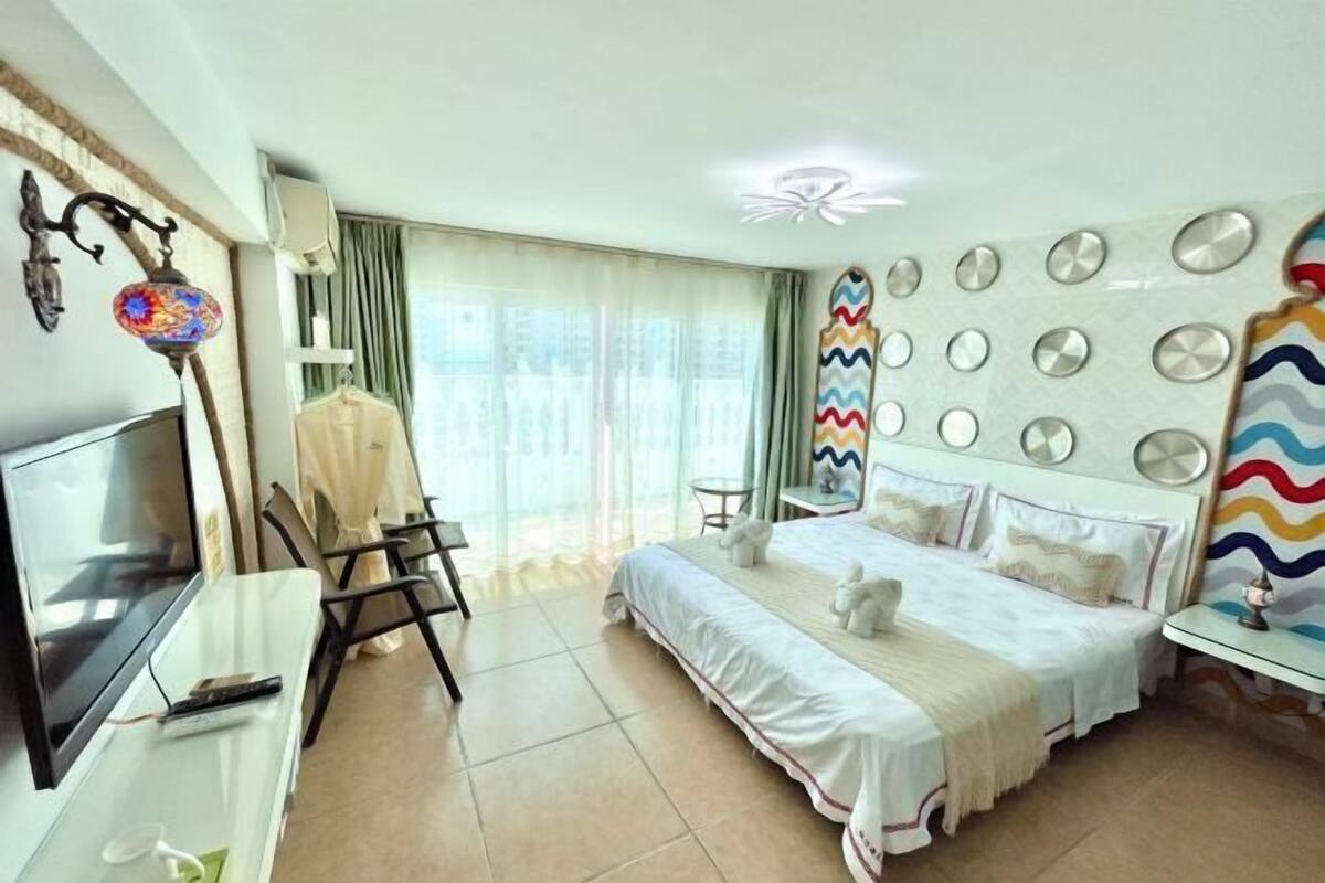Quarto de hotel com cama, televisão, escrivaninha e cadeira.