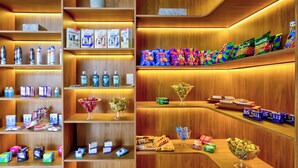 Loja bem organizada com prateleiras repletas de diversos produtos, incluindo itens de higiene, lanches e produtos para o lar.