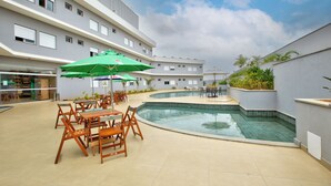 Um edifício moderno com piscina, área de estar ao ar livre e um pátio coberto.