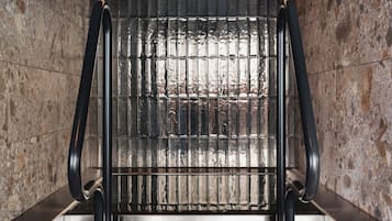 Um elevador moderno com acabamento metálico e parede texturizada ao fundo.
