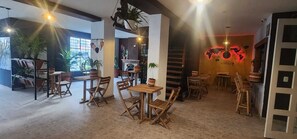 Um café acolhedor com móveis de madeira, plantas em vasos e um mural de um mapa-múndi.