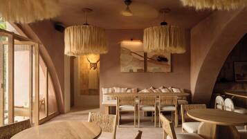 Um interior aconchegante com uma mesa de jantar de madeira, assentos acolchoados e luminárias pendentes.