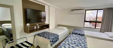 Quarto de hotel com cama, televisão, cadeira e janela com vista para a cidade.