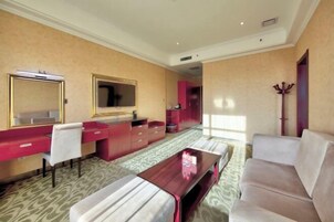 Quarto de hotel com cama, escrivaninha com cadeira, sofá, espelho e guarda-roupa.