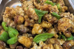 Close-up de um prato com pedaços de frango frito e pimentões verdes.