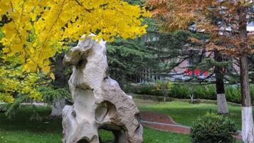 Escultura de pedra de um cavalo em um parque com árvores e uma trilha.