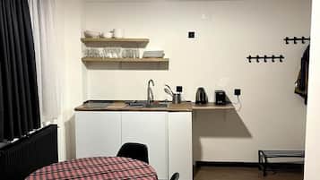Cozinha compacta com área de jantar, mesa com toalha xadrez e uma cadeira.