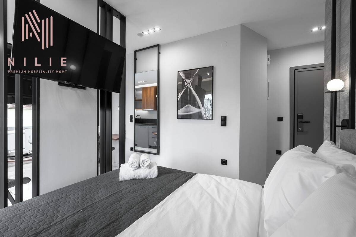Quarto de hotel moderno com uma cama, um espelho grande e uma TV de tela plana.