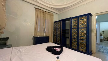 Um quarto com uma cama, um guarda-roupa com detalhes elaborados e uma janela com cortinas.