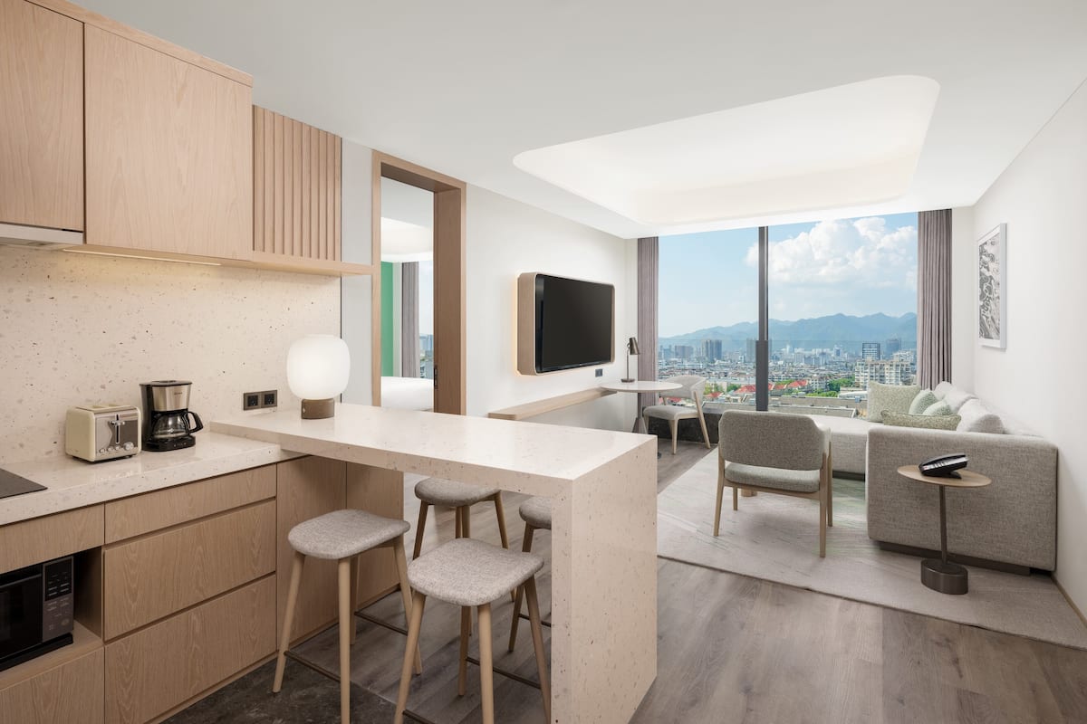 Uma cozinha moderna com área de bar, conjunto de mesa e cadeiras e um sofá.