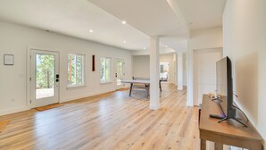 Um quarto espaçoso com soalho em madeira, uma janela grande e uma televisão de tela plana sobre uma mesa de madeira.