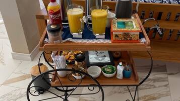 Um carrinho de café da manhã com uma garrafa de Evian, dois copos de suco de laranja, uma cafeteira e um bule.