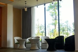 Um interior moderno com grandes janelas, uma luminária no teto e uma fileira de cadeiras.