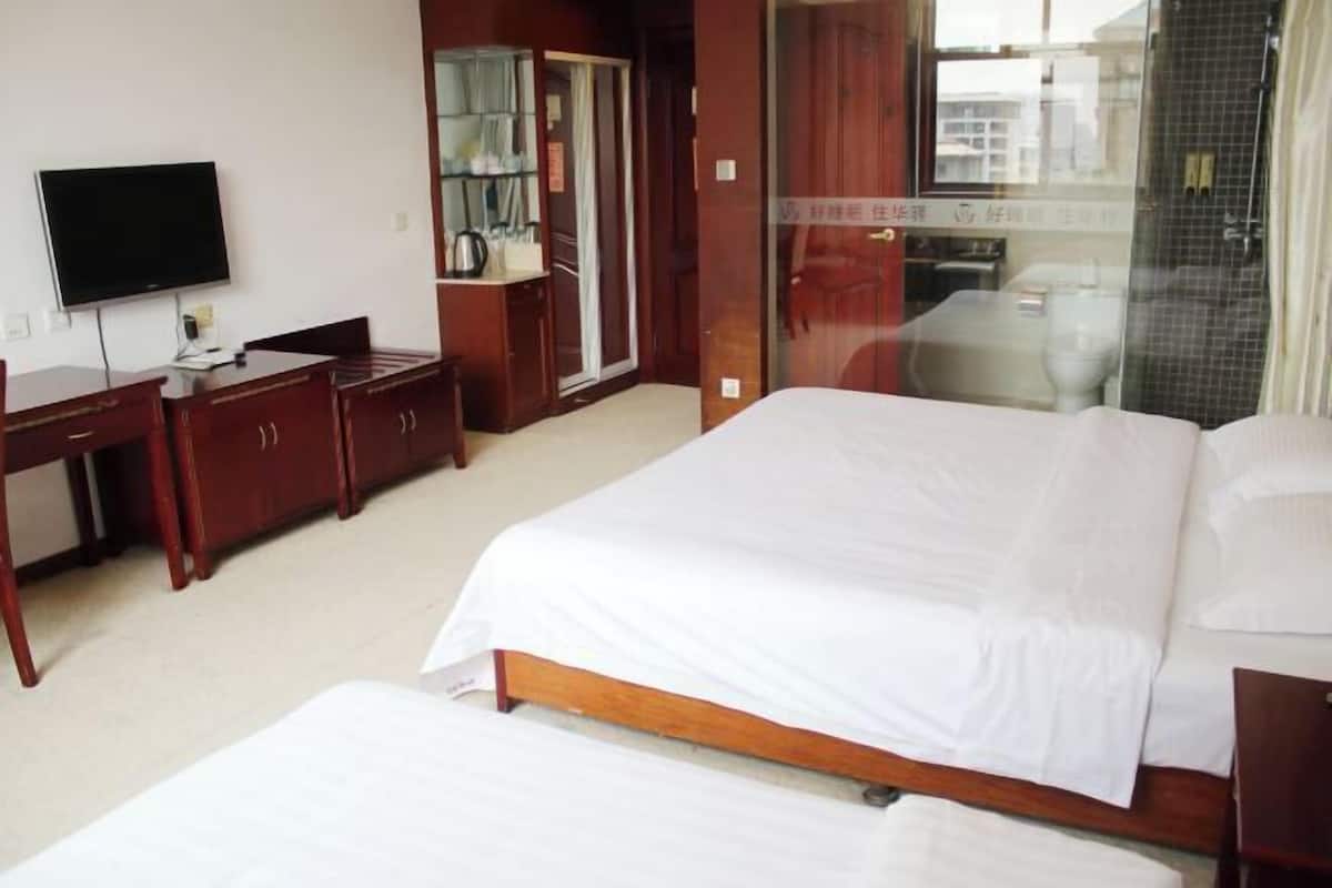 Quarto de hotel com cama, escrivaninha, televisão, armário e banheiro.