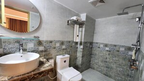 Um banheiro com espelho redondo, pia, vaso sanitário e chuveiro.