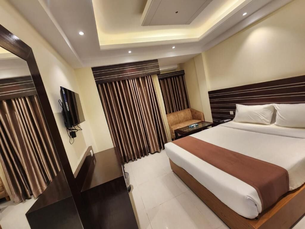 Quarto de hotel moderno com uma cama grande, uma escrivaninha, uma cadeira e uma televisão.
