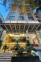 Exterior do Hotel 22Land Saigon, com fachada moderna, grandes janelas de vidro e entrada bem iluminada.