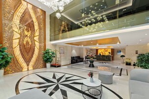 Um saguão de hotel moderno com um design de parede grande e detalhado, uma recepção e uma área de estar espaçosa.