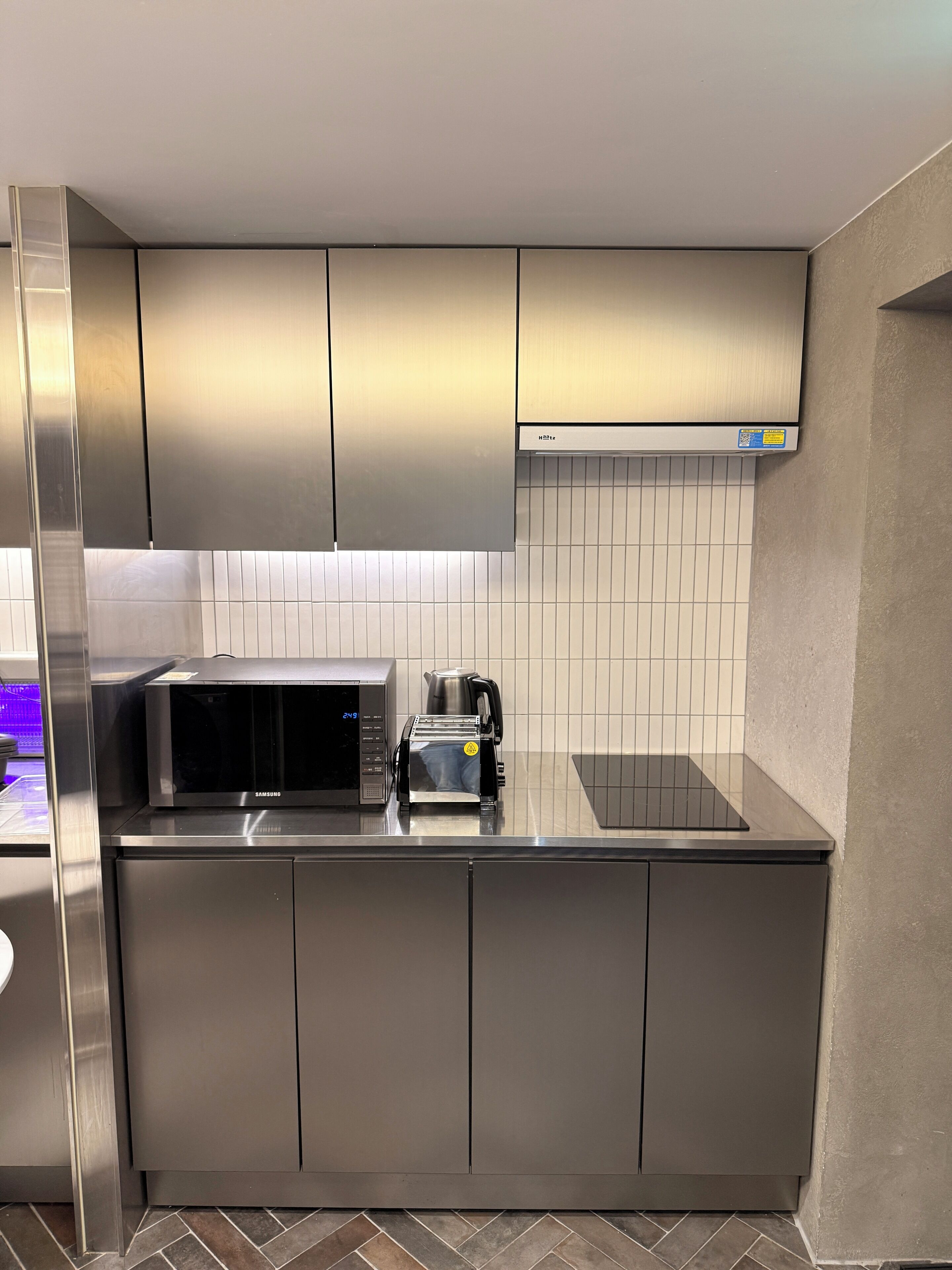 Cozinha moderna com eletrodomésticos de aço inoxidável, micro-ondas e cafeteira.