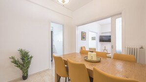 Uma área de refeições com uma mesa de madeira, cadeiras amarelas e um vaso com planta.