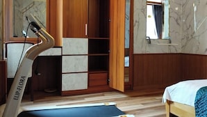 Quarto com guarda-roupa de madeira, esteira, cama com cobertor azul e parede com padrão marmorizado.