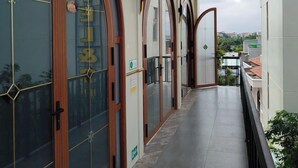 Um corredor com portas arqueadas, piso de azulejos e vista para a cidade.