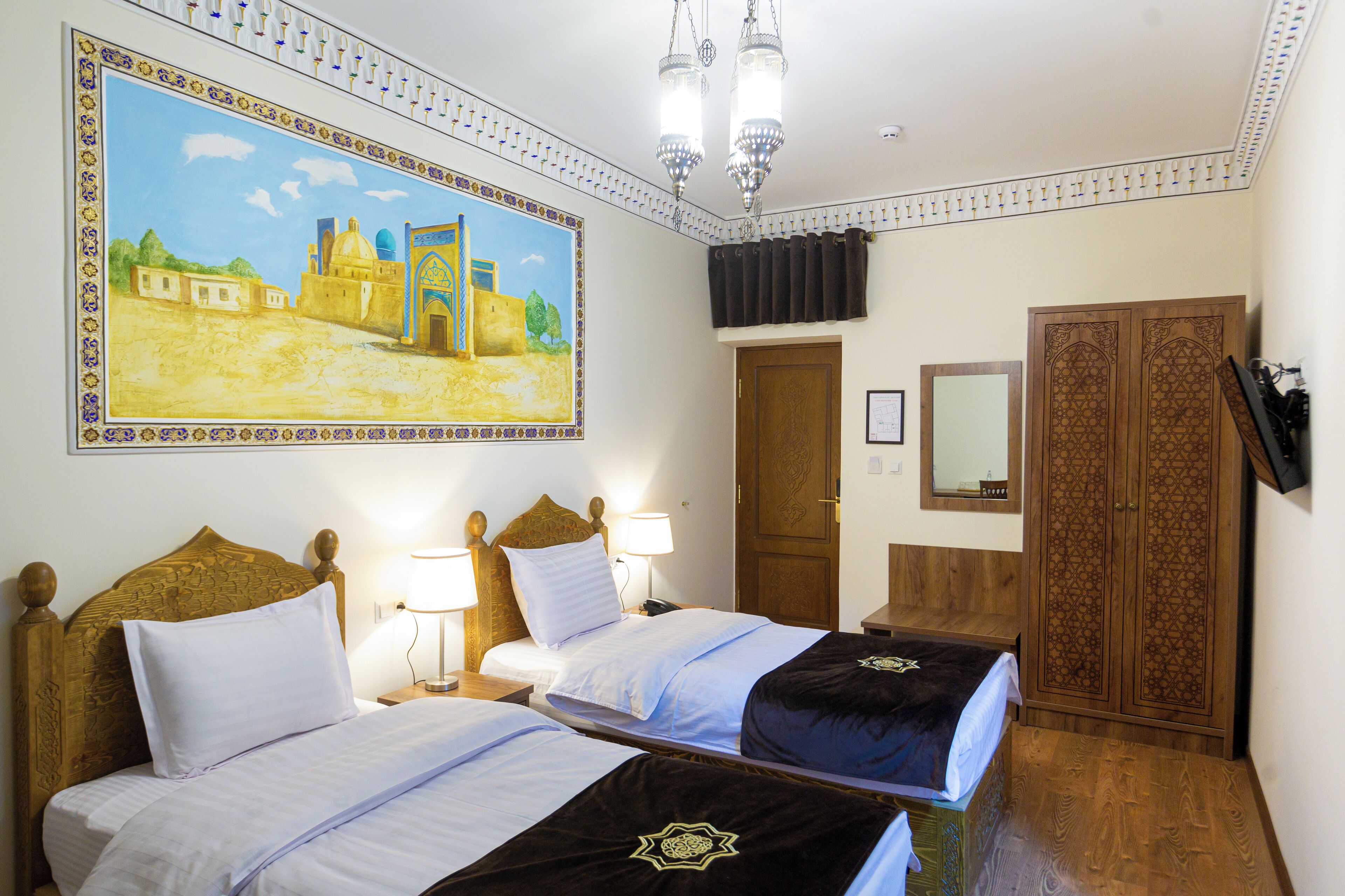 Quarto de hotel com duas camas, um quadro de um edifício histórico, um lustre e um guarda-roupa.