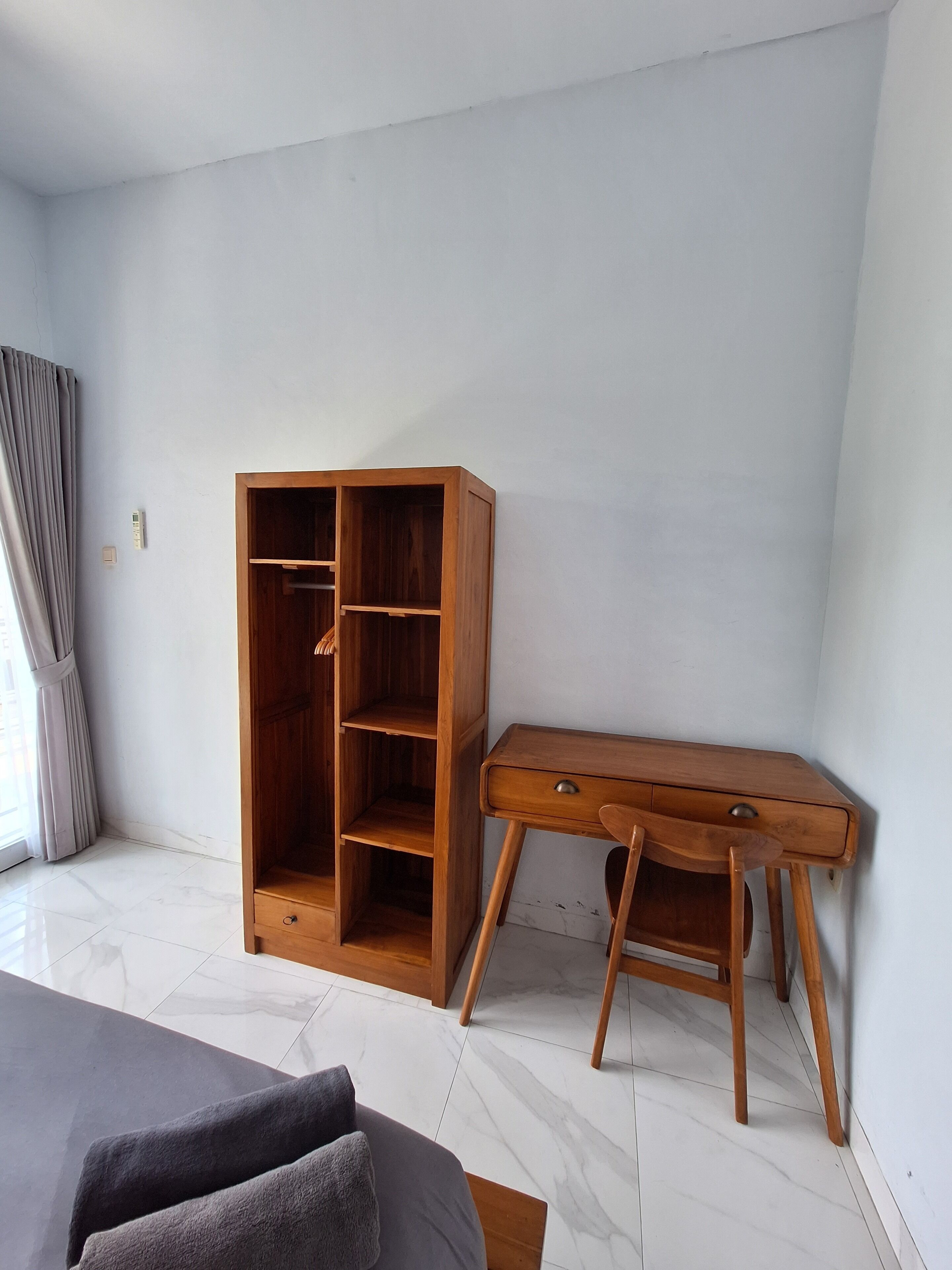 Quarto com cama, guarda-roupa de madeira e escrivaninha com cadeira.