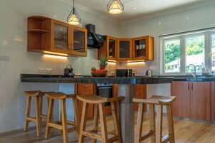 Uma cozinha moderna com armários de madeira, uma ilha central com banquetas e iluminação pendente.