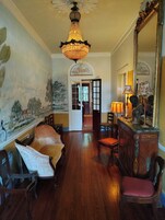 Quarto com lustre, mobiliário de madeira, um espelho grande e um mural na parede.