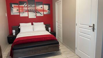 Quarto com cama, mesas de cabeceira, parede vermelha e porta.
