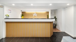 Uma receção com um logótipo de estrela, um painel de ripas de madeira e chão de azulejos pretos.