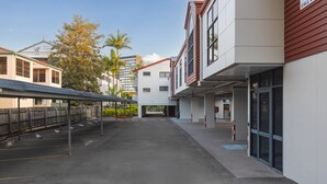 Um edifício moderno com galeria coberta, área de estacionamento e céu claro.