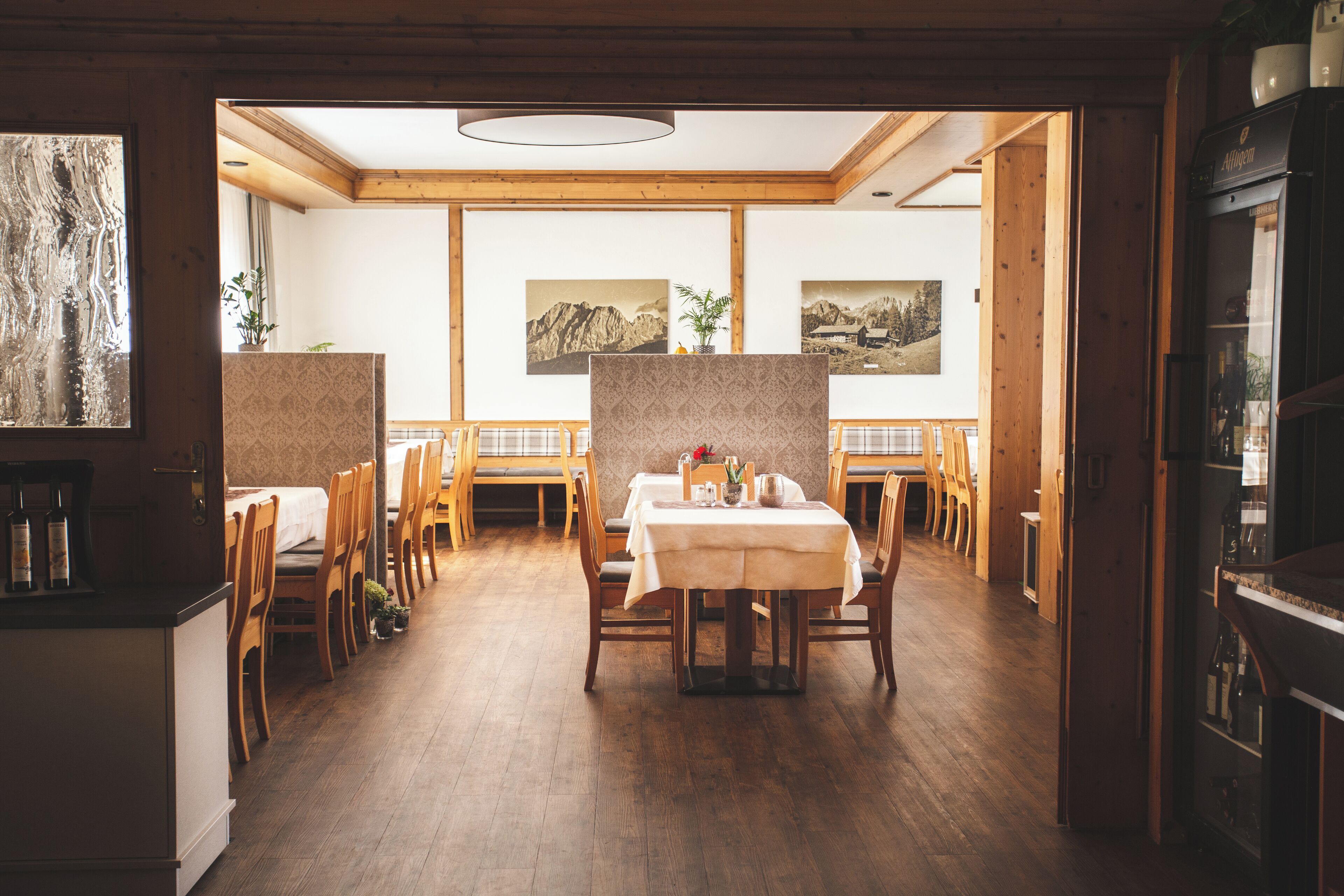 Um restaurante com soalho de madeira, mesas, cadeiras e obras de arte nas paredes.