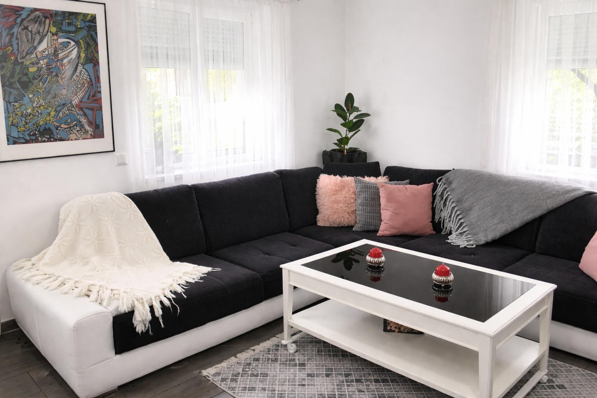 Uma sala de estar moderna com um sofá preto, poltrona branca e uma mesa de centro de vidro.