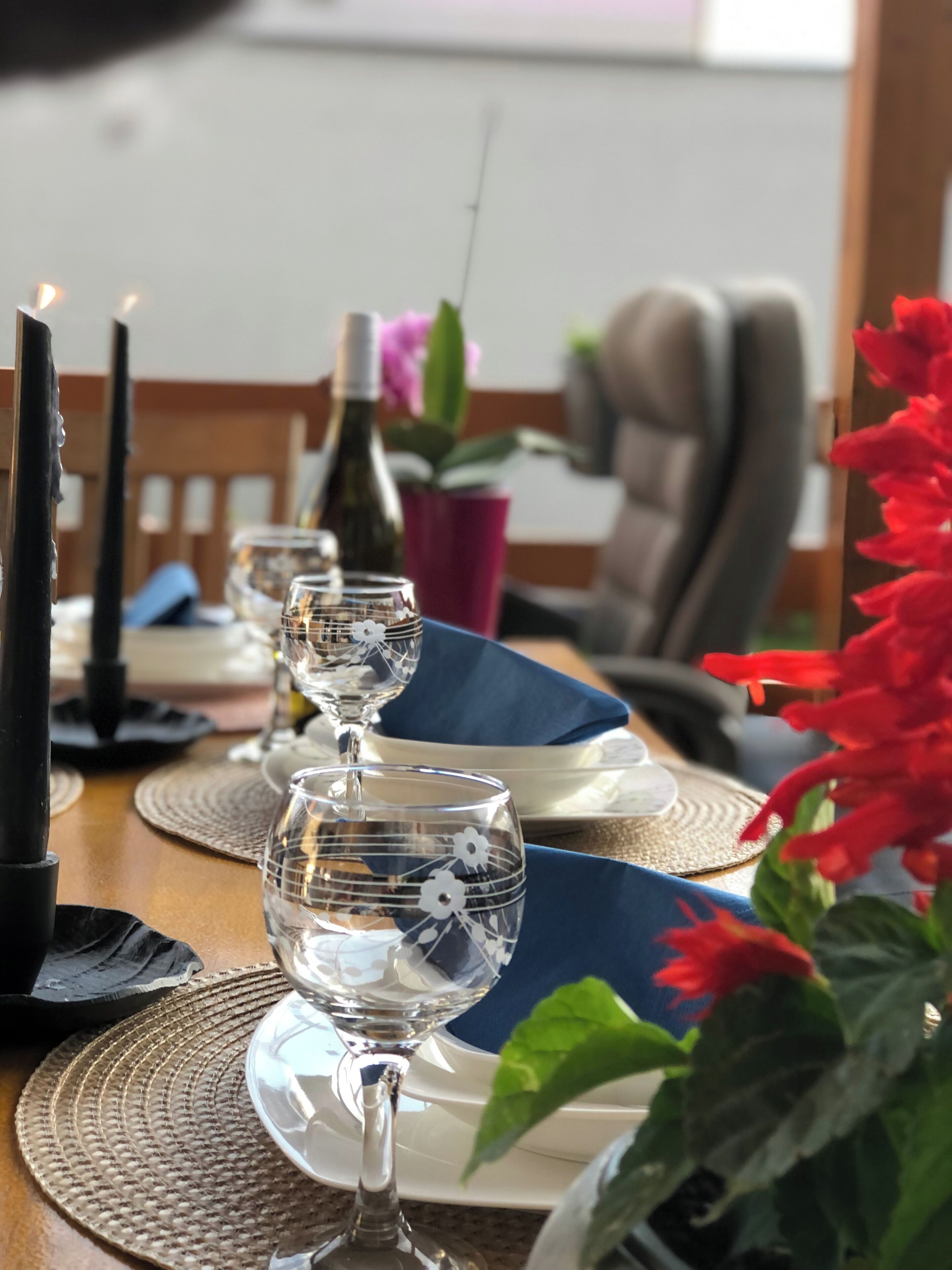 Uma mesa de jantar posta com taças de vinho, pratos e uma vela.
