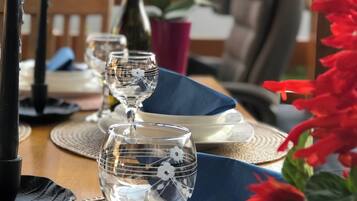 Uma mesa de jantar posta com taças de vinho, pratos e uma vela.