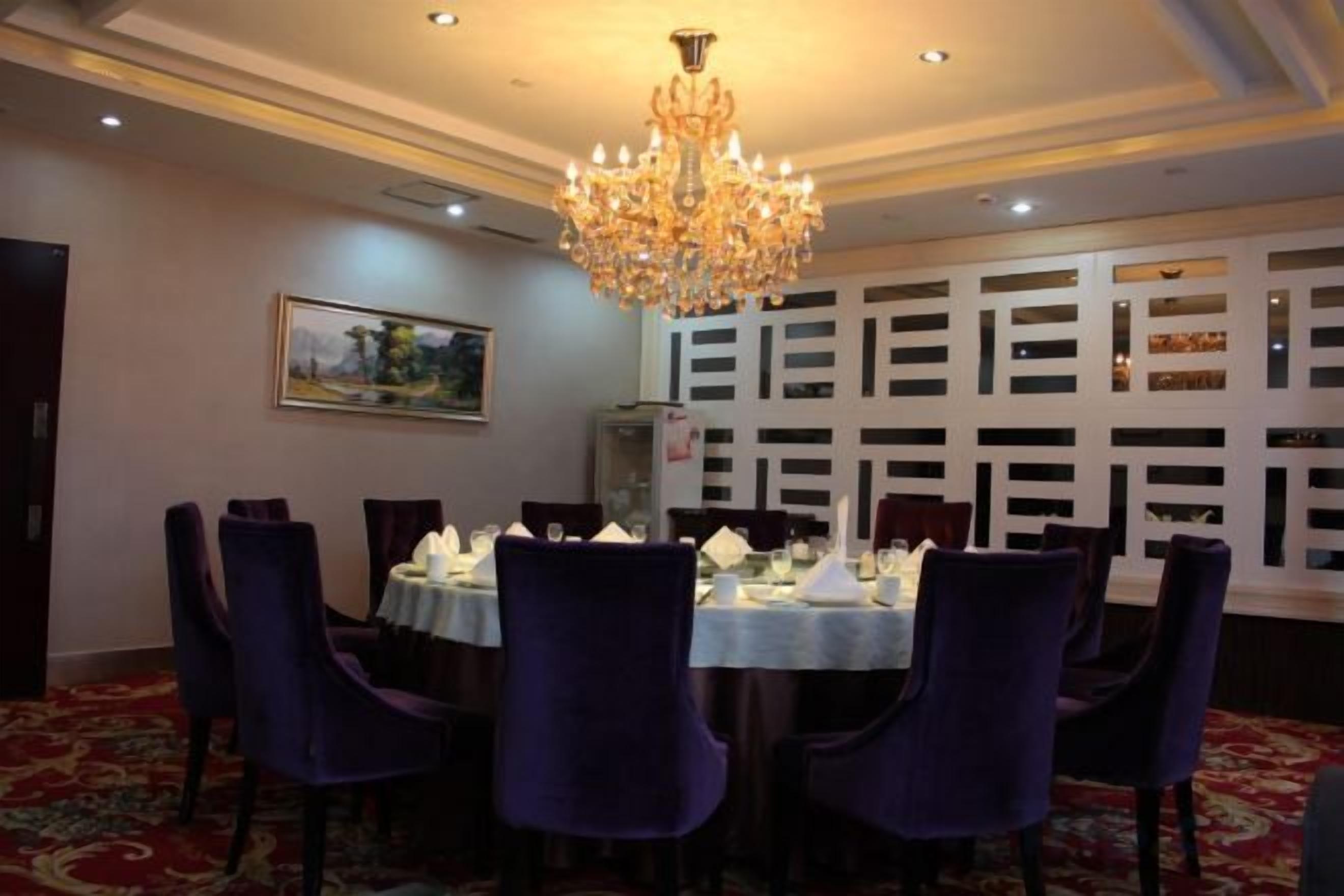 Uma sala de jantar com lustre, mesa redonda e cadeiras roxas.