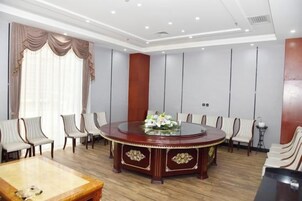 Uma sala de conferência com uma mesa redonda, cadeiras e uma pequena mesa.