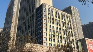 Um edifício alto e moderno com uma grade de janelas e base de pedra.