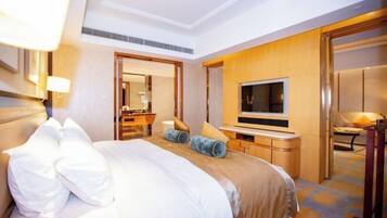 Quarto de hotel com uma cama grande, televisão, escrivaninha e espelho.
