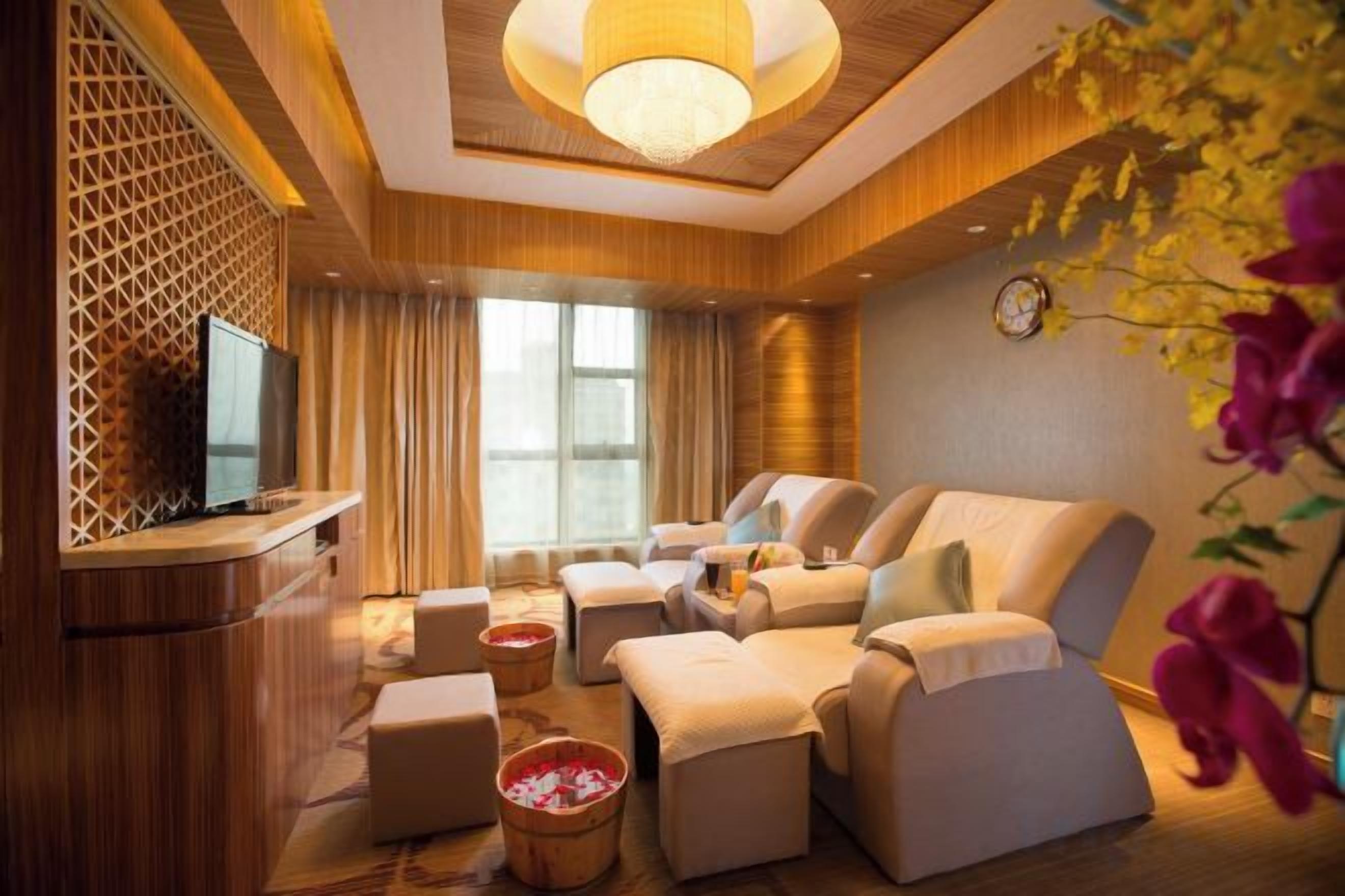 Quarto de hotel moderno com sofá, televisão e decoração na parede.