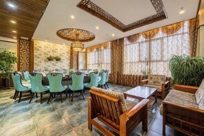Uma área de refeições com uma mesa redonda e cadeiras, um sofá e uma planta grande.