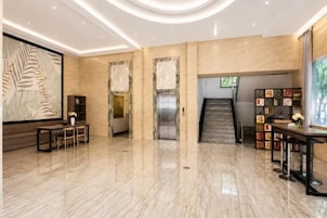 Um hall moderno com piso de mármore, balcão de recepção, elevador e escada.