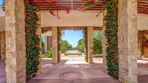 Um pavilhão de pedra com plantas trepadeiras e uma vista desobstruída de uma fonte ao fundo.