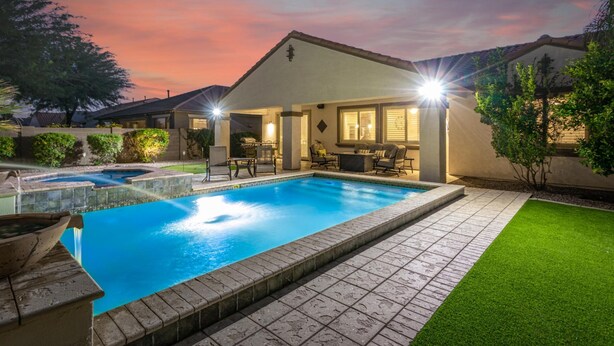 Quintal residencial com piscina, varanda com mobiliário de exterior e gramado bem cuidado.